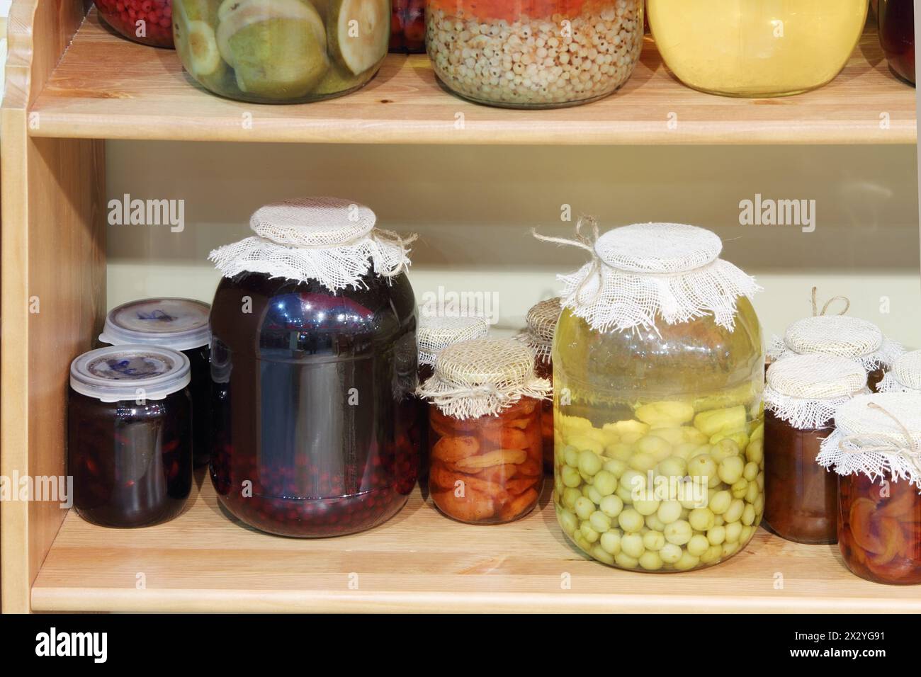 Big and small jars with jam, stewed and pickled mushrooms are on ...