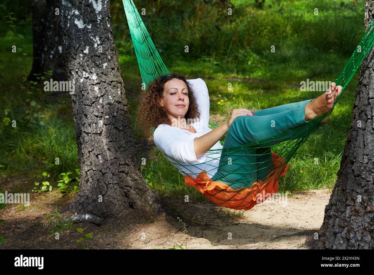 Young woman lies with dreamy view in hammock suspended between two ...