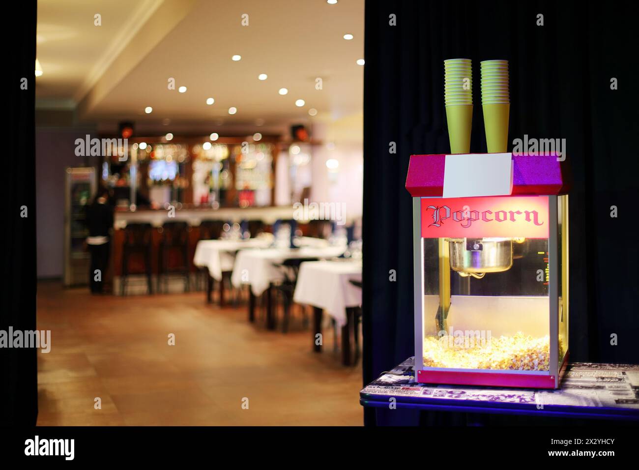 Popcorn machine in background of restaurant and bar in movie theater ...