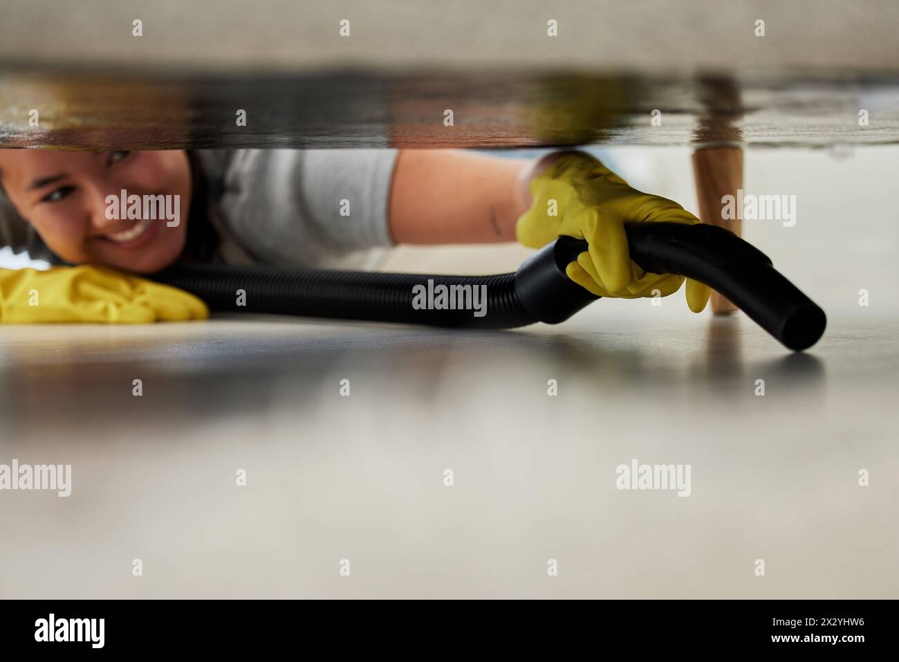 Woman, vacuum and cleaning under sofa in living room for dust, hygiene ...