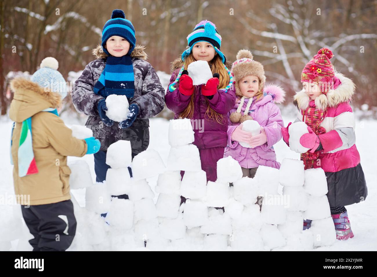 Five children build wall from snow bricks in winter park Stock Photo ...