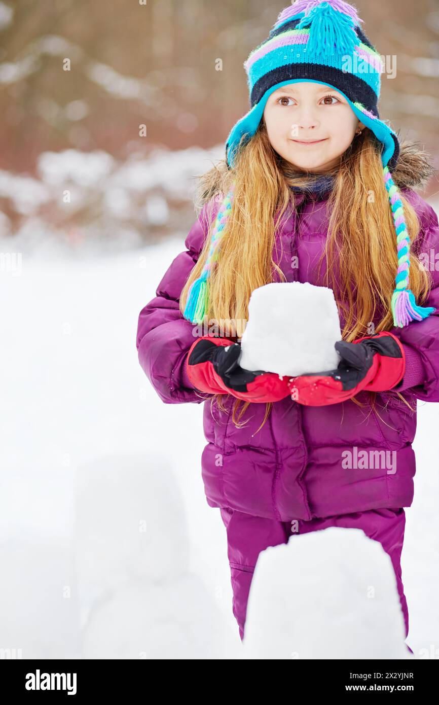 Portrait of girl who stands behind barrier made from snow blocks and ...