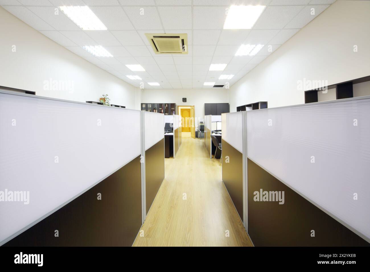Corridor and empty working areas with desktops separated by partitions ...