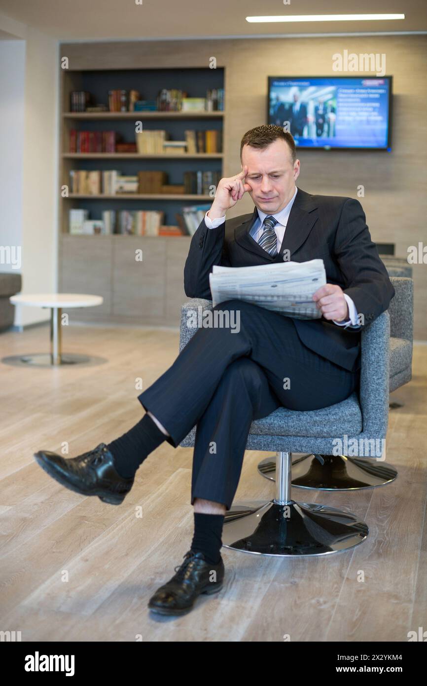 A serious businessman in a suit and tie reading a newspaper Stock Photo ...