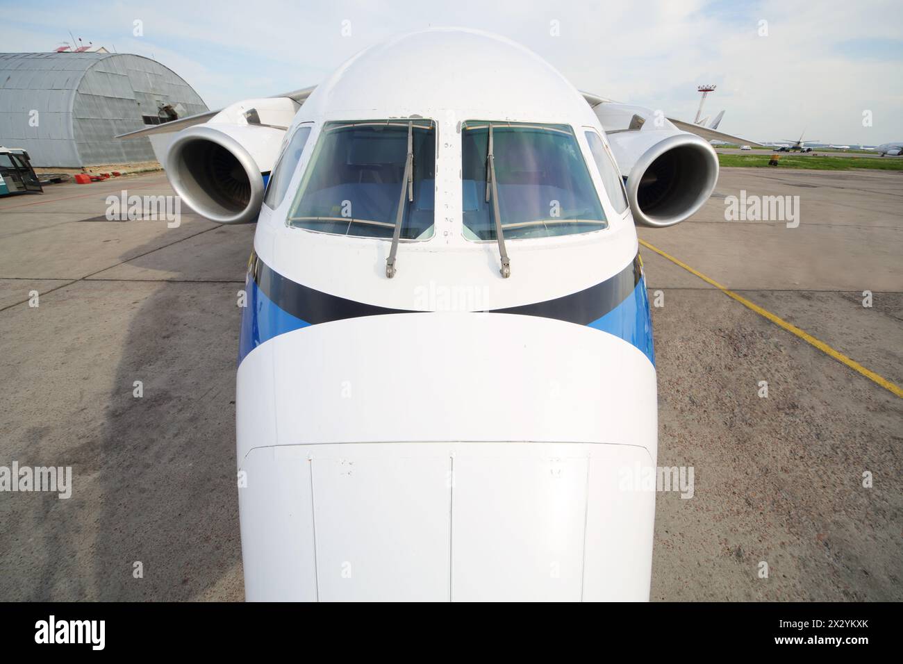 Cockpit of big white-blue passenger airliner at airport near hangar ...