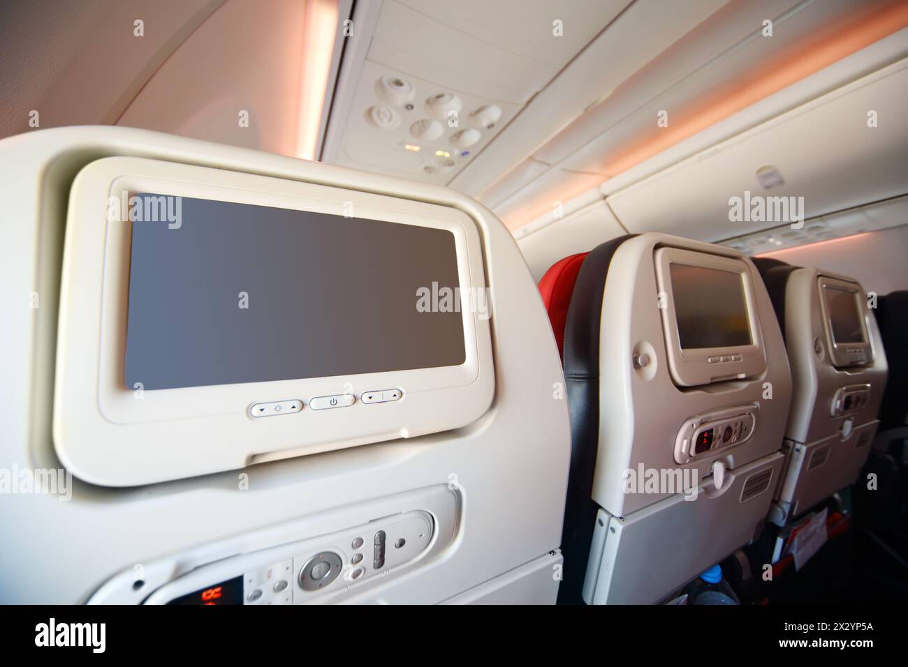 Screens for passengers in back of soft seats in modern airplane Stock ...