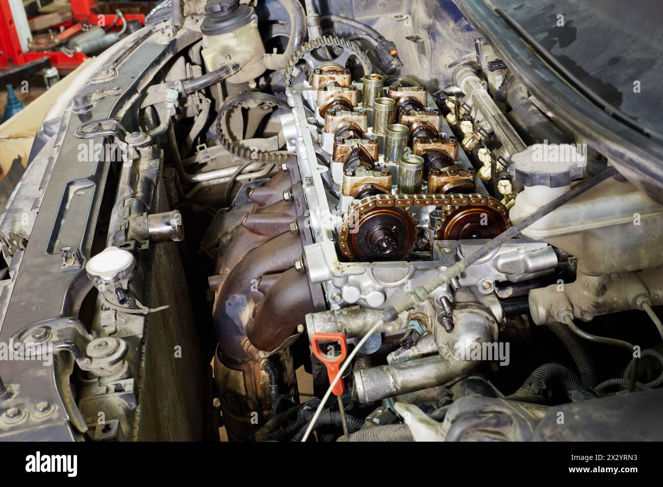 Four-cylinder car engine with cover off under open car hood Stock Photo ...
