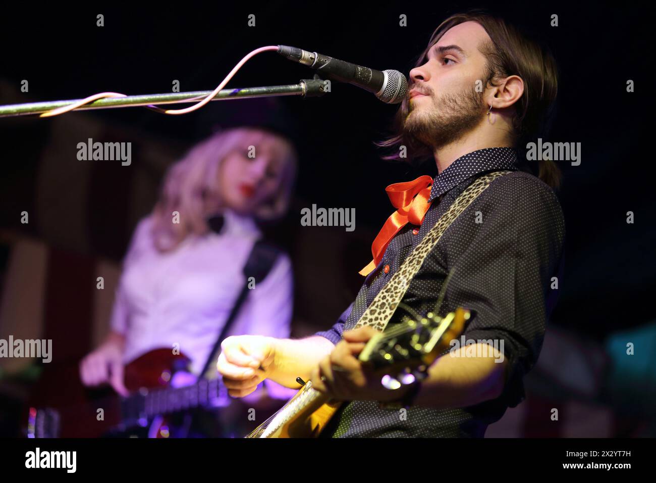 The singer with a guitar and a red ribbon performing on stage Stock ...