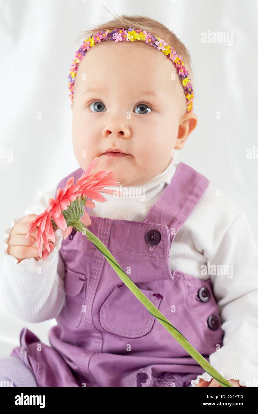 Portrait of little girl in violet pinafore dress with headband in form ...
