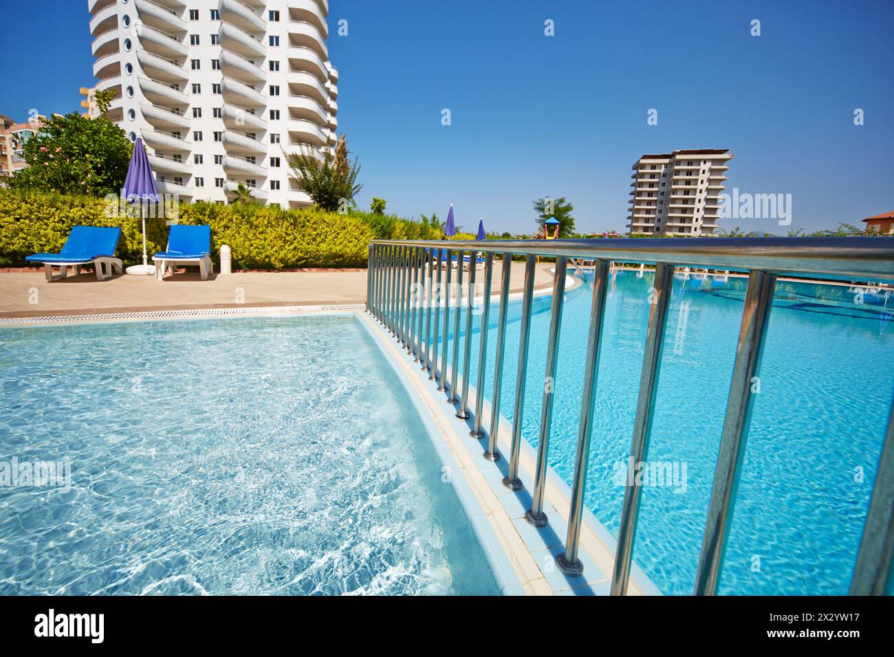 Pools, poolside with deck-chairs and umbrellas , view from separating ...