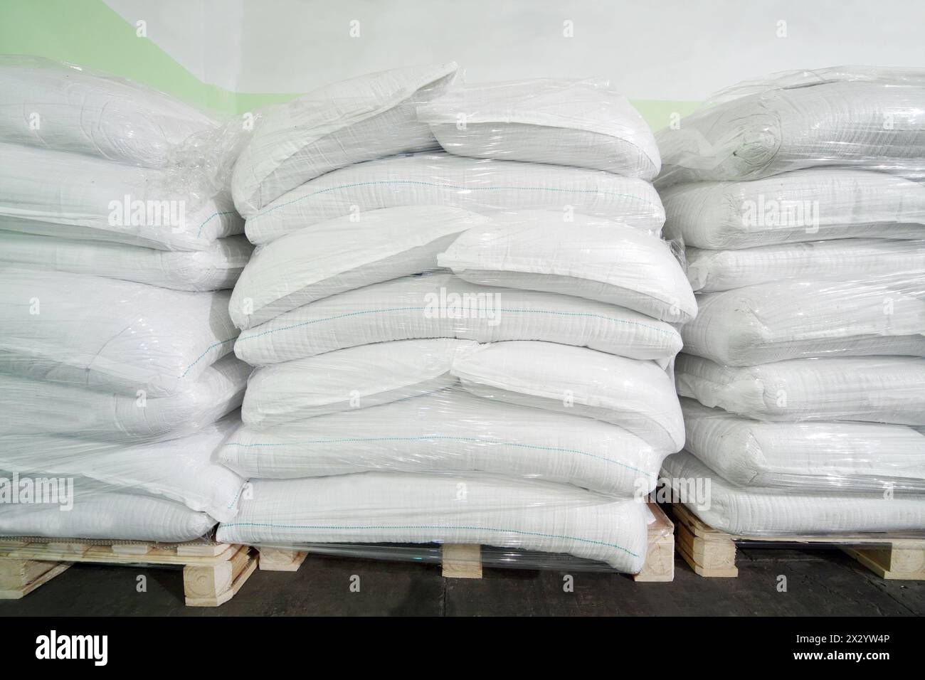 Three piles of big white sacks at large warehouse in modern factory ...