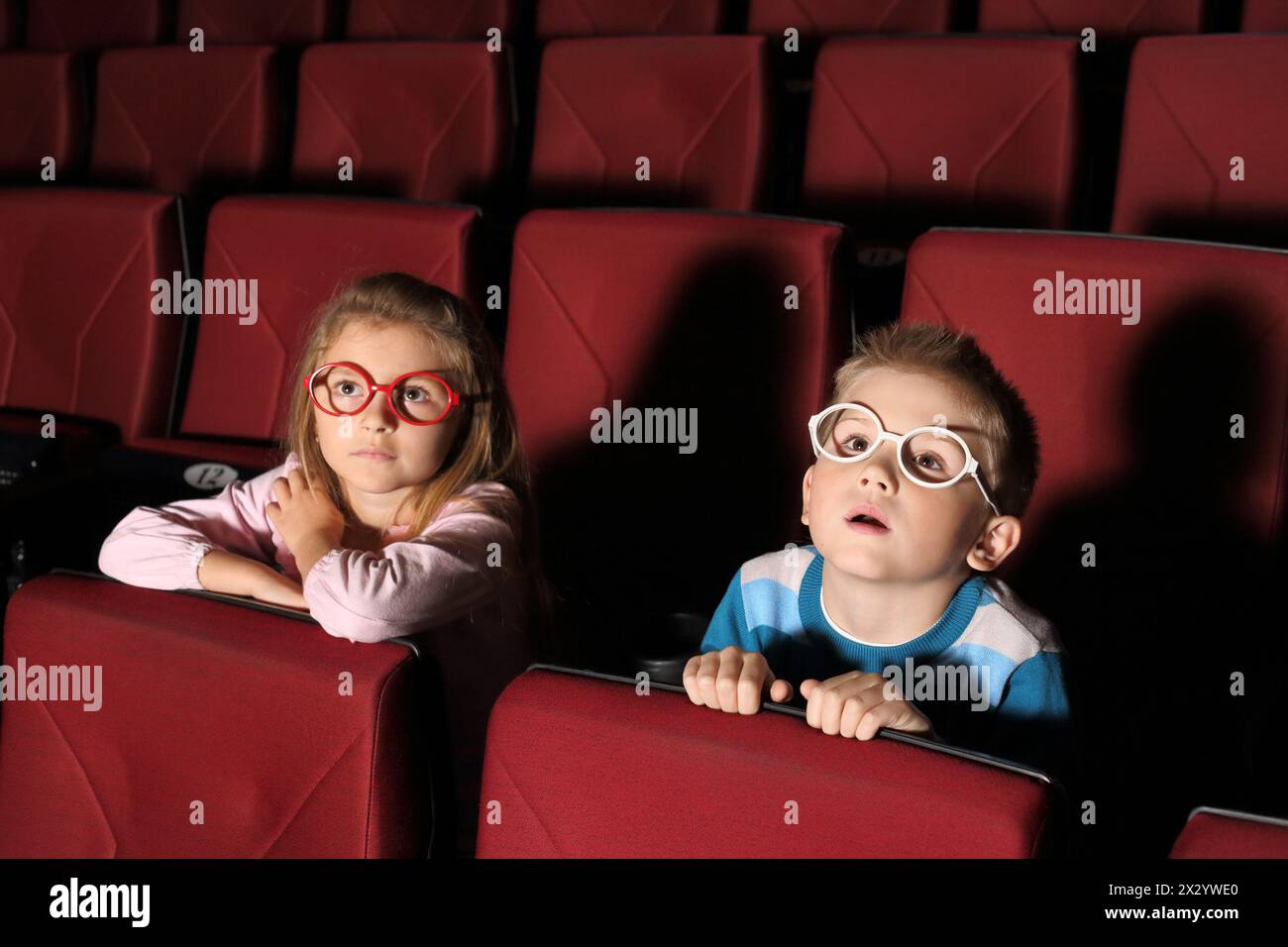Little boy and girl watching a movie with interest in an empty cinema ...