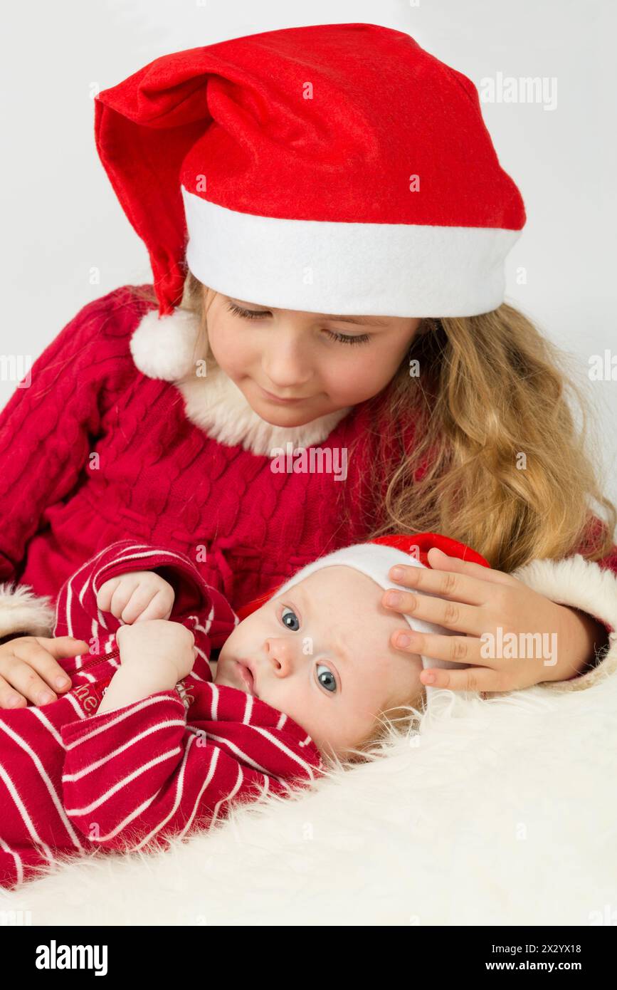 Little girl with baby lie in the hats of Santa Claus, focus on a baby ...