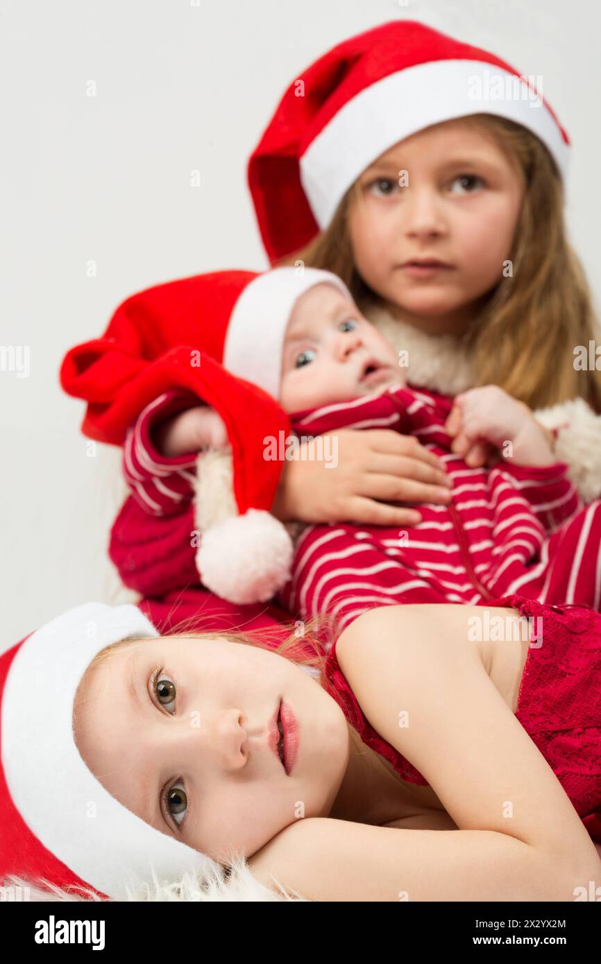Three children lie on fur in the hats of Santa Claus Stock Photo - Alamy
