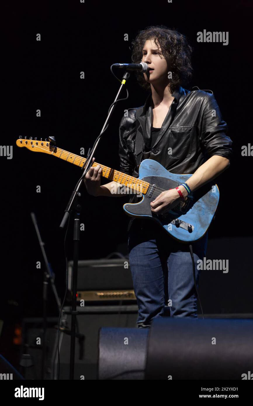Singer with guitar of rock band performs in front of group on stage ...
