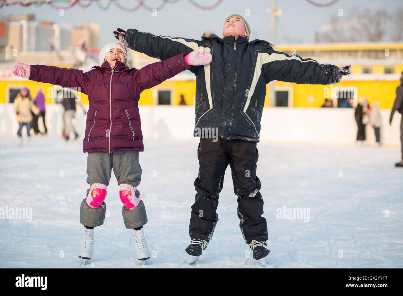 Boy and girl skating on rink and making hands to the side Stock Photo ...