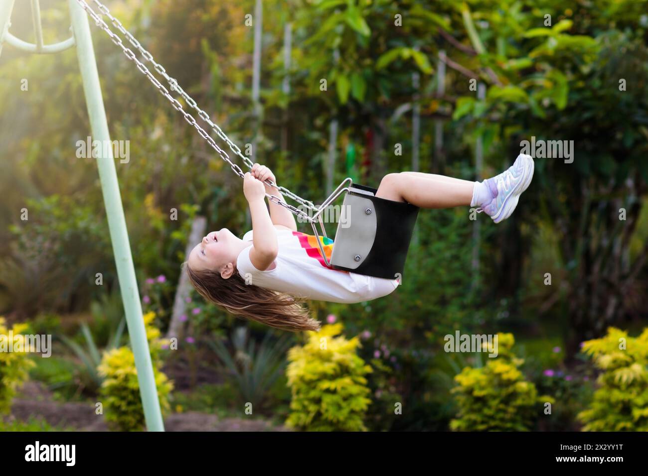 Child swinging on playground on sunny summer day in a park. Kids swing ...