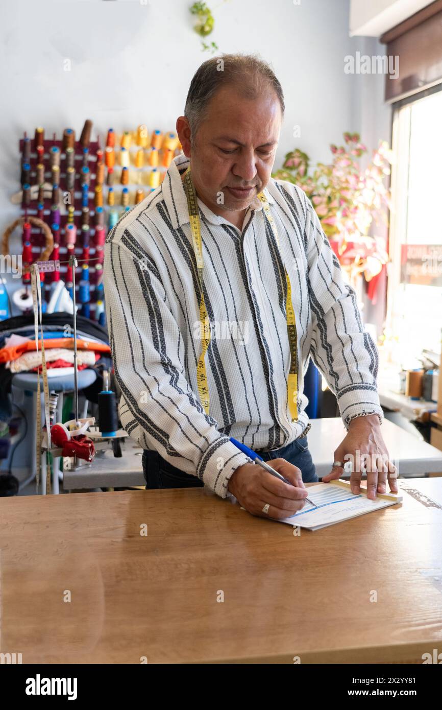 Man giving a receipt to a customer in his sewing shop Stock Photo - Alamy