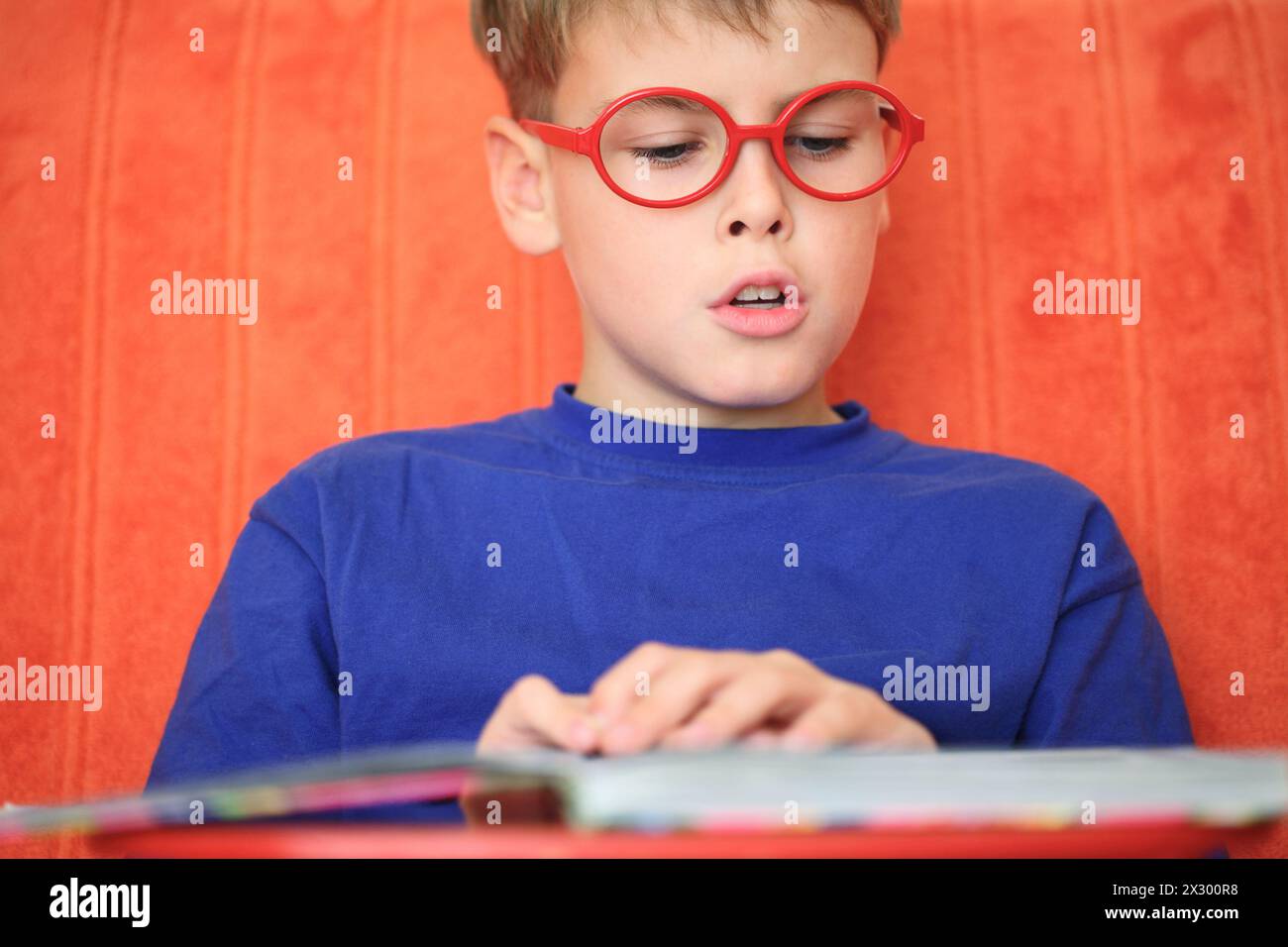 Boy with glasses reading a book intently Stock Photo - Alamy