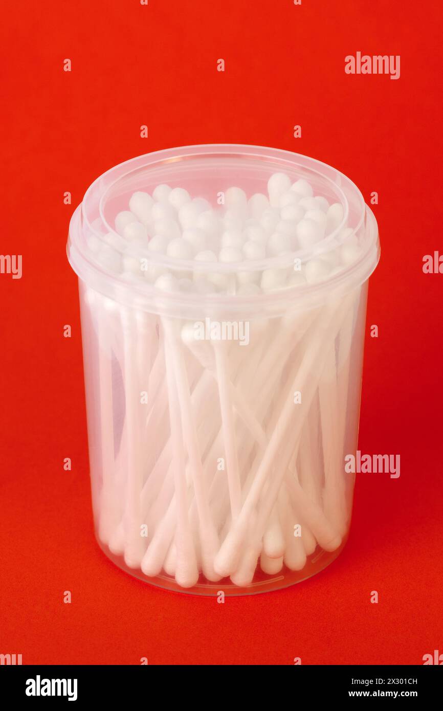 White cotton sticks in plastic container on a red background Stock ...