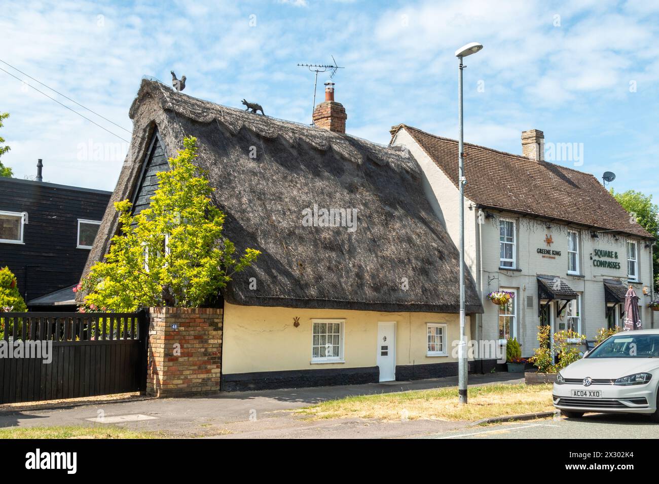 Animal finials on a thatched roof, a cat chasing a hen, and a ...