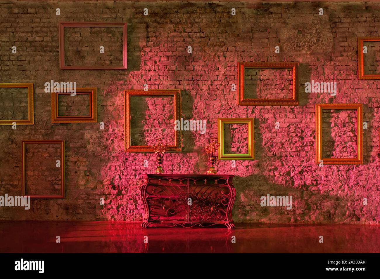 Empty picture frames on the brick wall and forged chest with ...