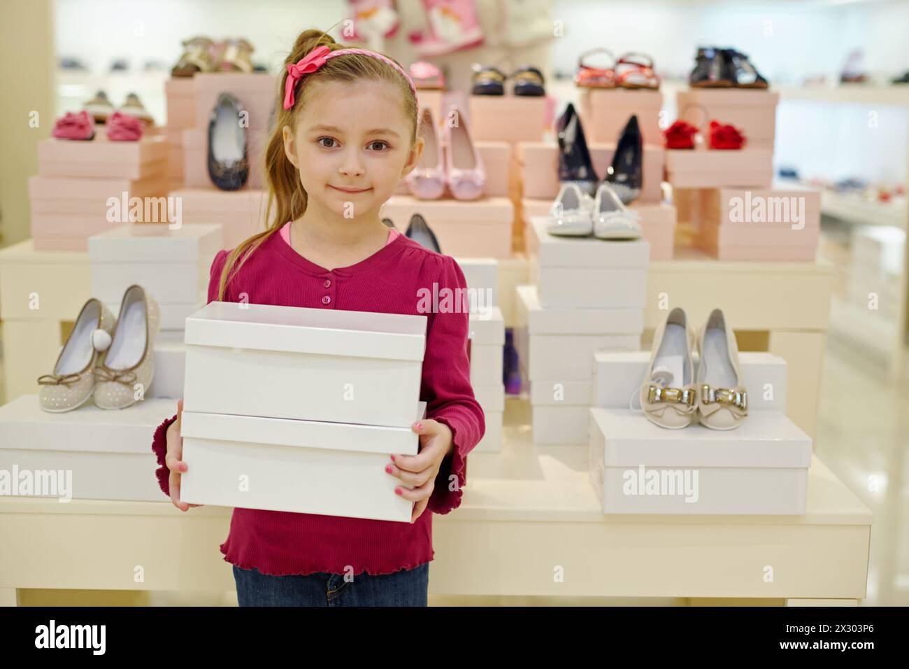 Little girl stands and holds two shoe boxes in shoe store Stock Photo ...