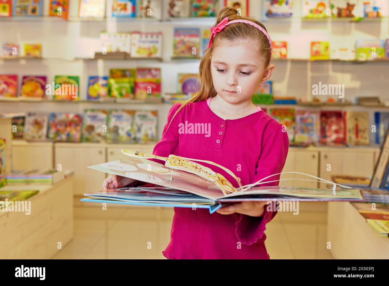 Little girl views fold-out book on anatomy in book department at store ...