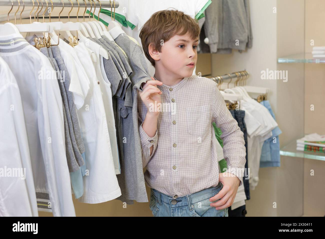 The boy chooses clothes in the childrens clothing store Stock Photo - Alamy