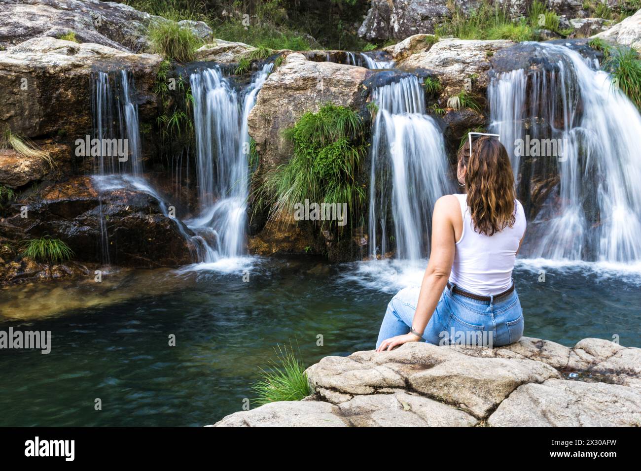 Woman sitting on a rock in front of the Loureza pools. Oia - Galicia ...