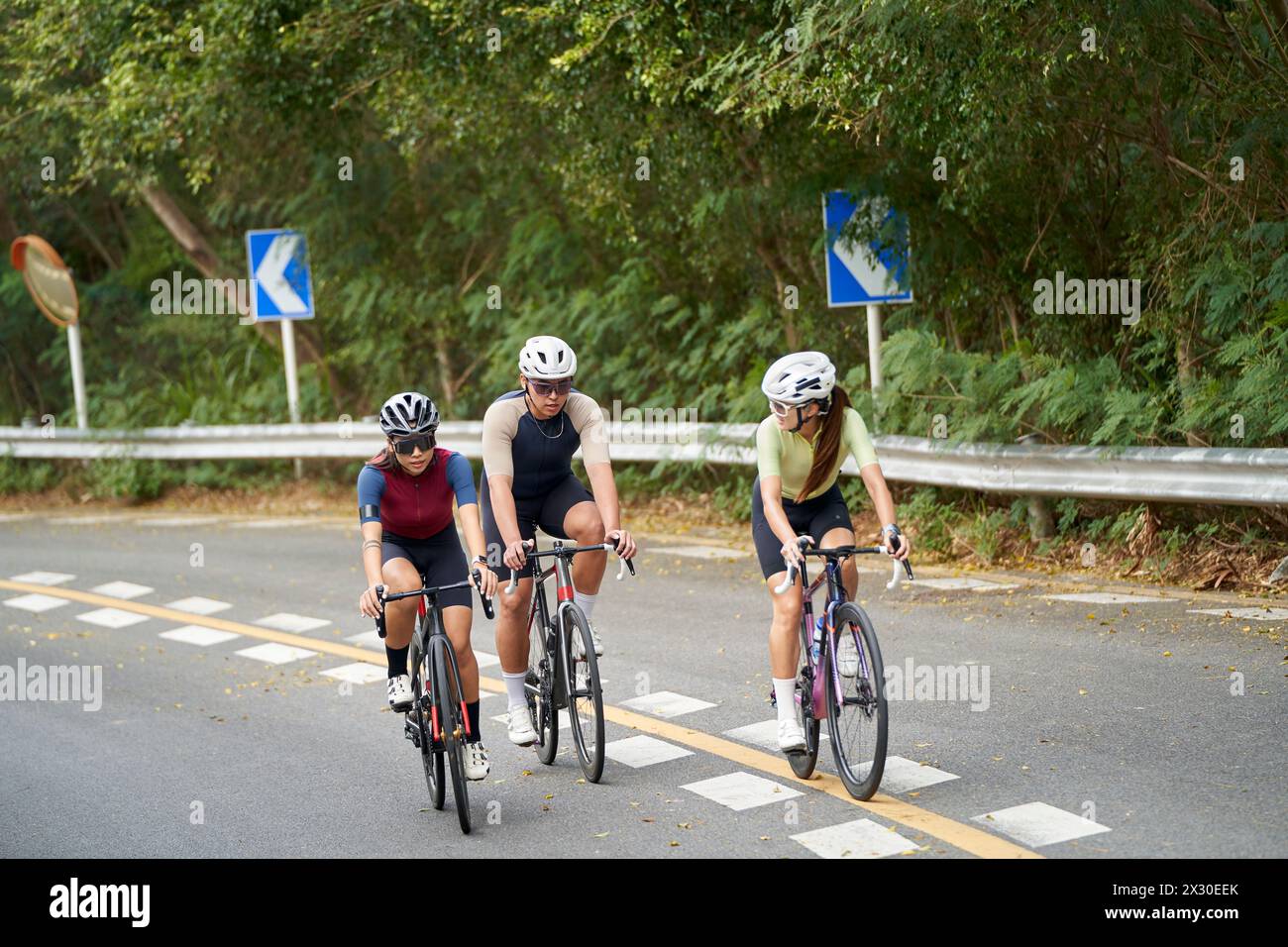 three young asian cyclists riding bike outdoors on rural road Stock ...