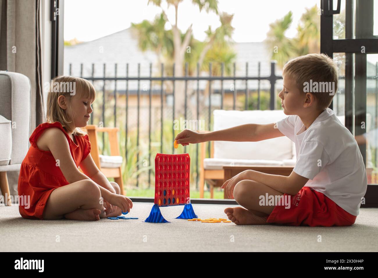 Siblings engrossed in a strategic board game, enhancing their logic ...