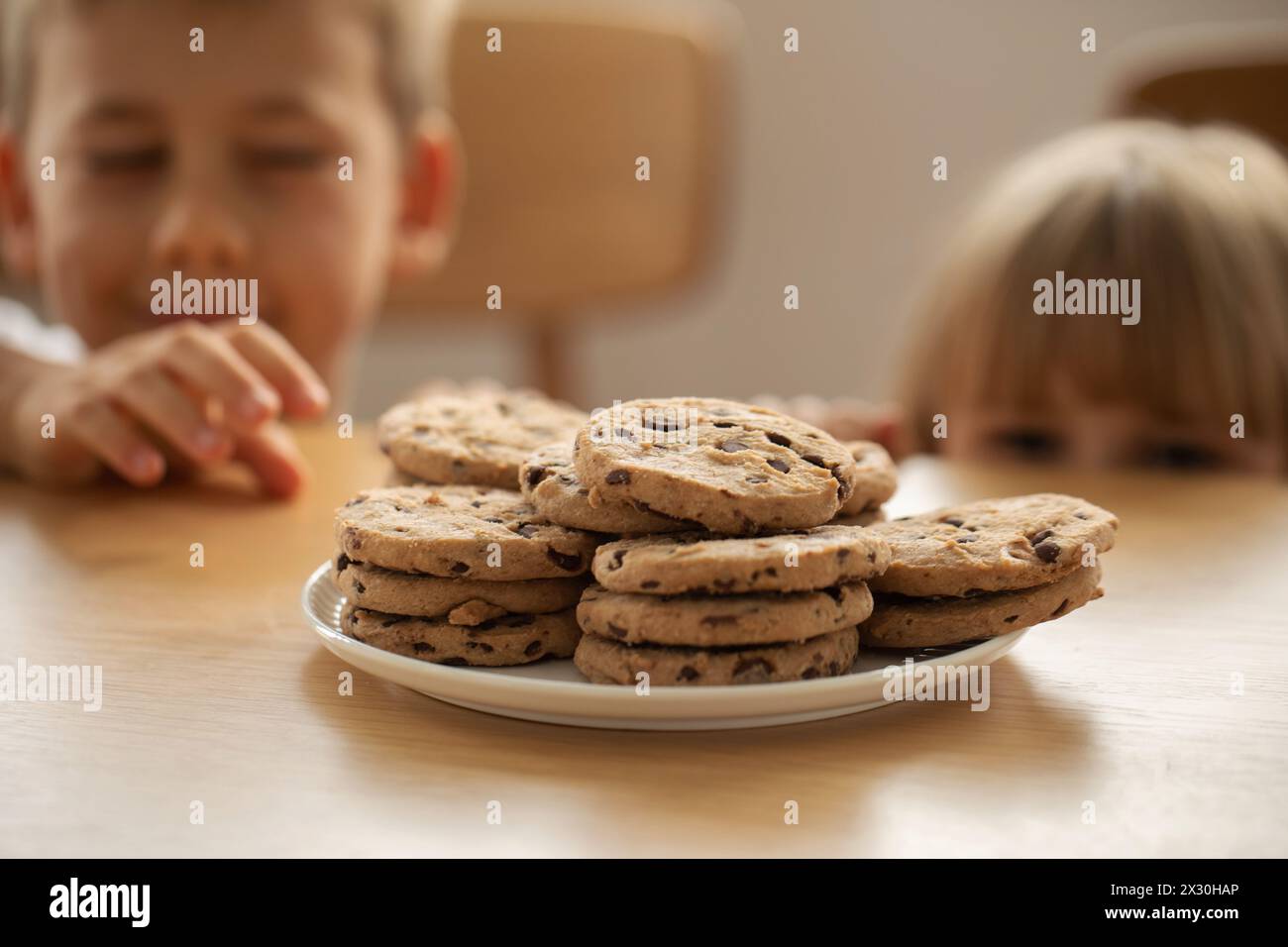 Children peeking over a tempting stack of freshly baked chocolate chip ...