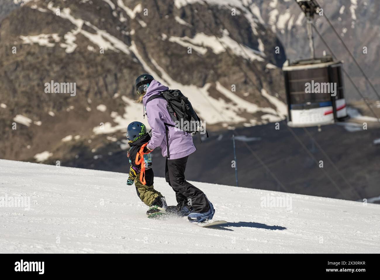 Kid with mom on snowboard. Learning snowboard little kid. Parent with ...