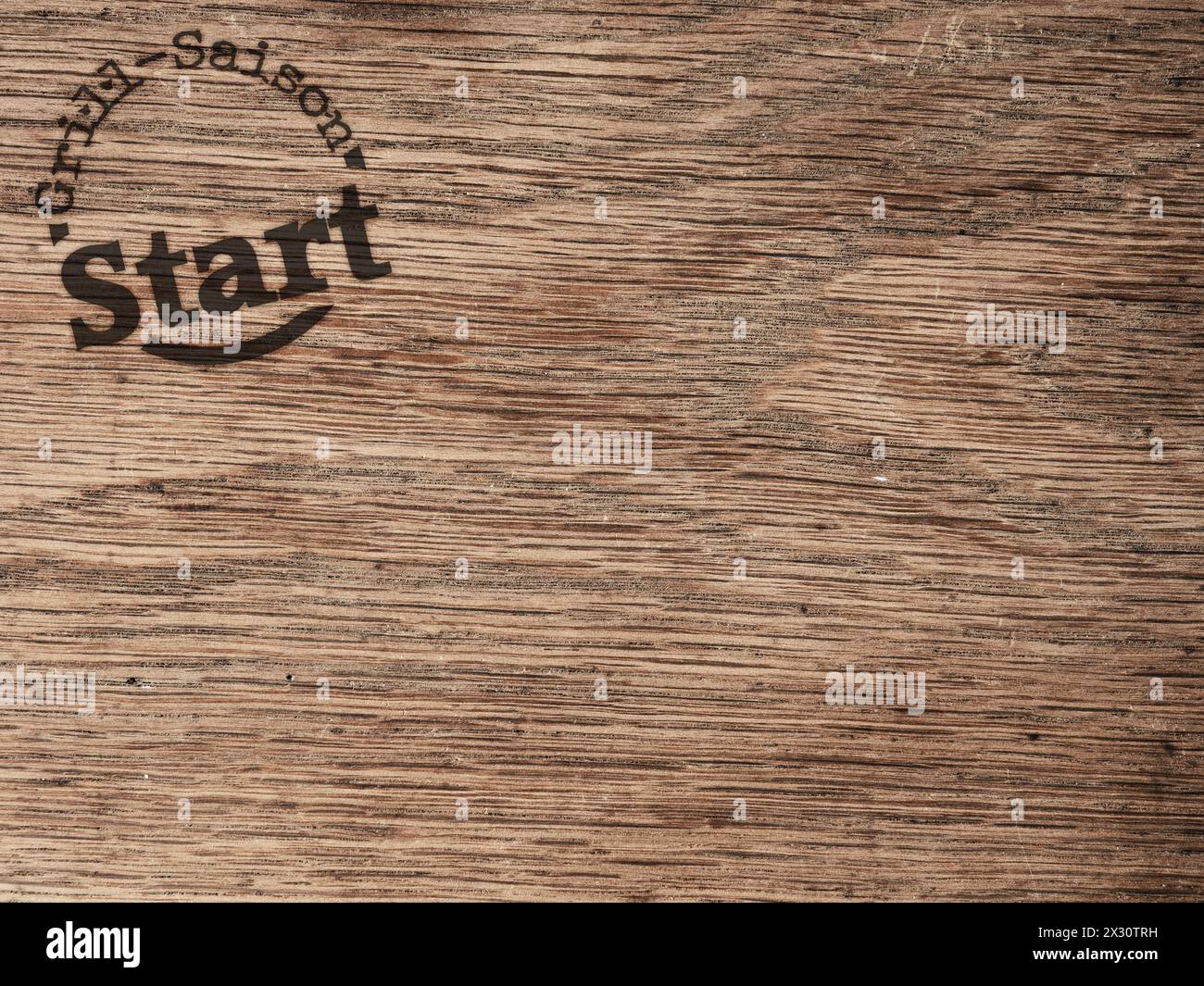 Stamp with text grill saison start on texture of an old used oak plank ...