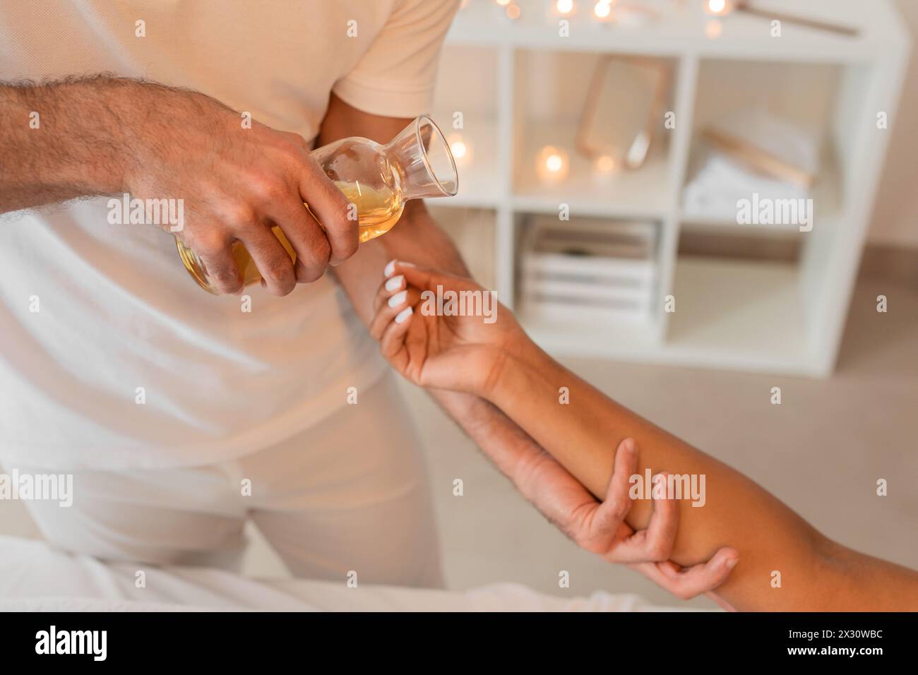 Massage therapist pouring oil on woman's hand Stock Photo - Alamy