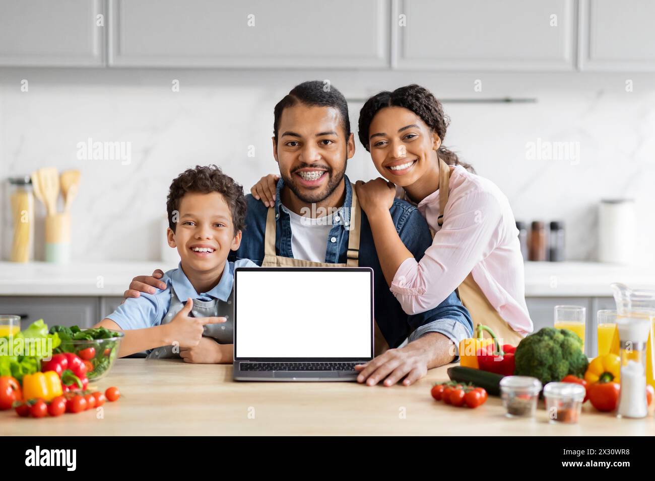 Smiling loving black family showing laptop with white screen Stock ...