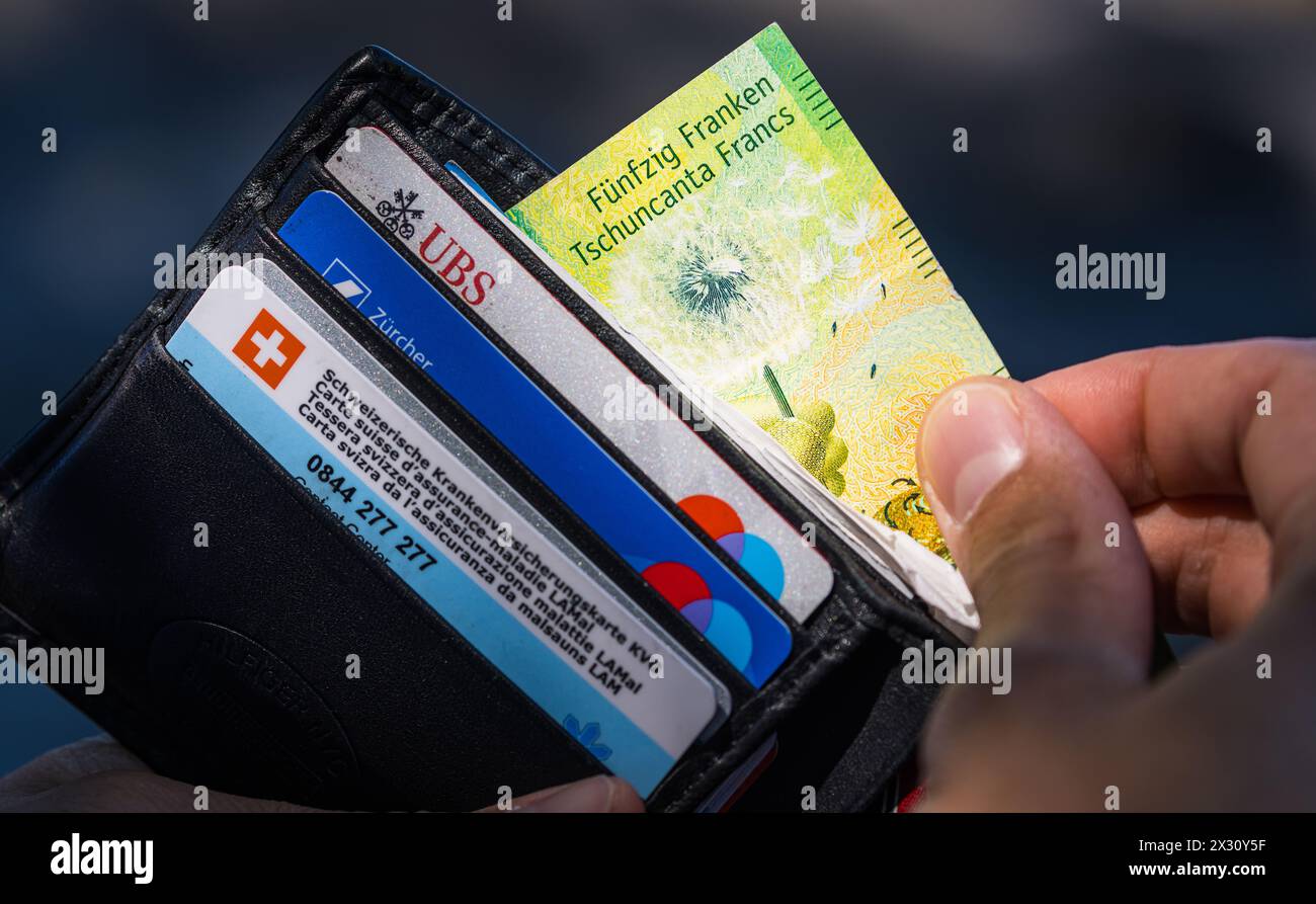 Ein junger Mann zieht eine Banknote mit dem Wert von fünfzig Schweizer ...