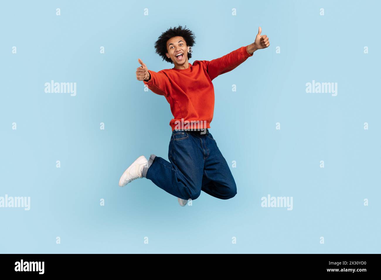 Energetic guy leaping with thumbs up gesture Stock Photo - Alamy