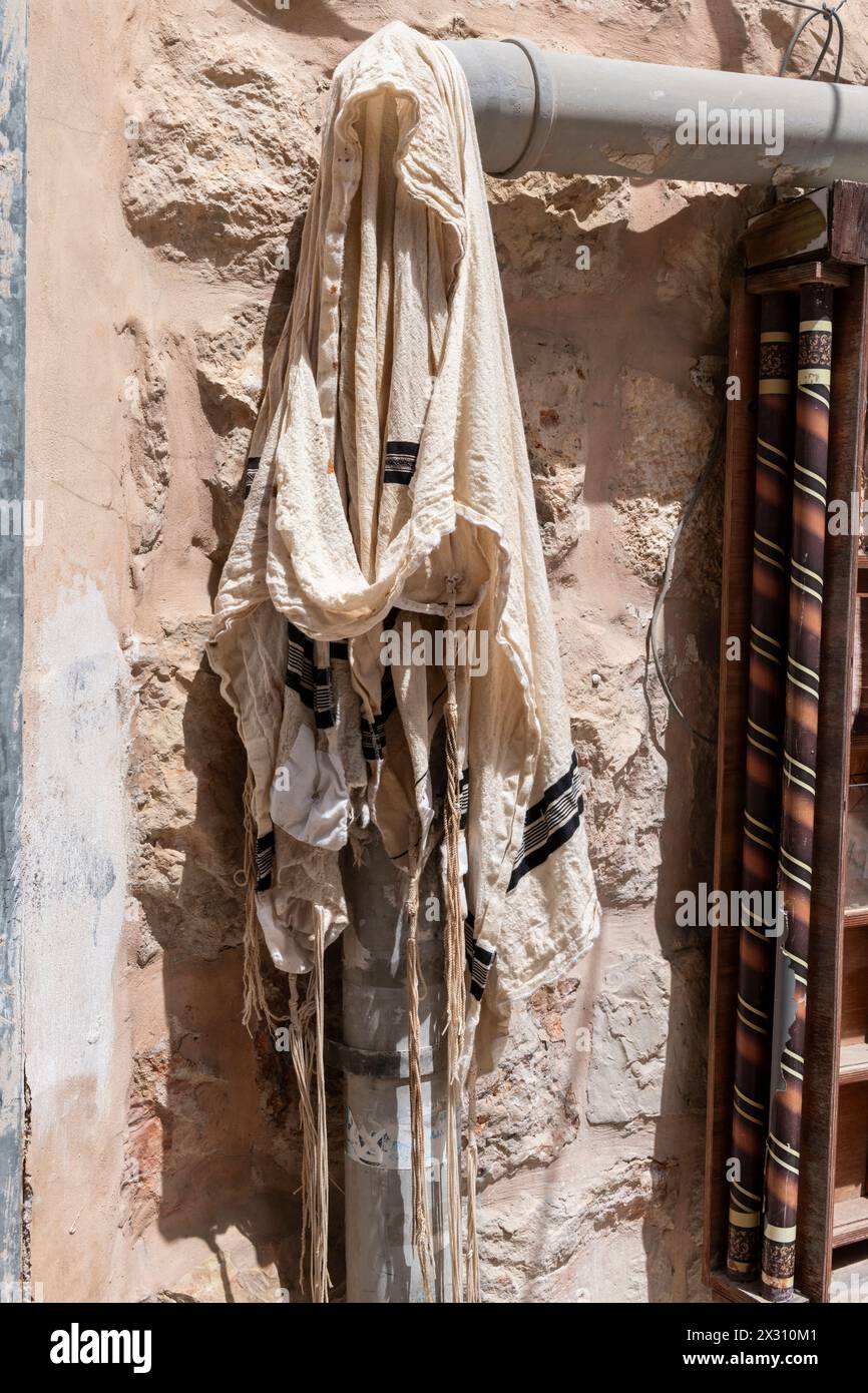 A dirty, torn and tattered Jewish prayer shawl or tallit hanging from a ...