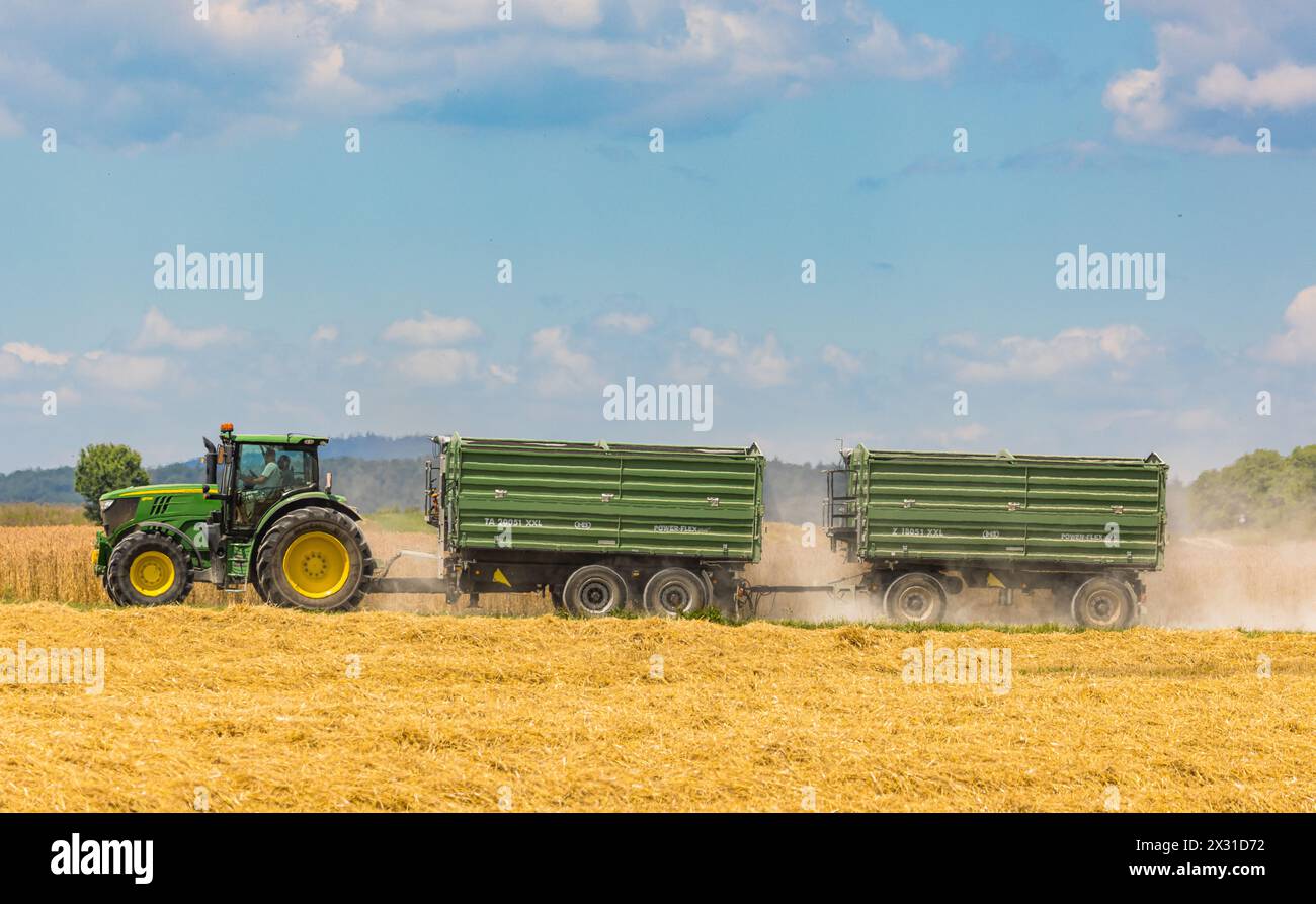 Ein Landwirt fährt mit seinem John Deere Traktor und zwei Anhängern auf ...