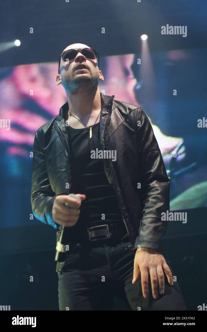 Lead singer of music group performs on stage with microphone on hand ...