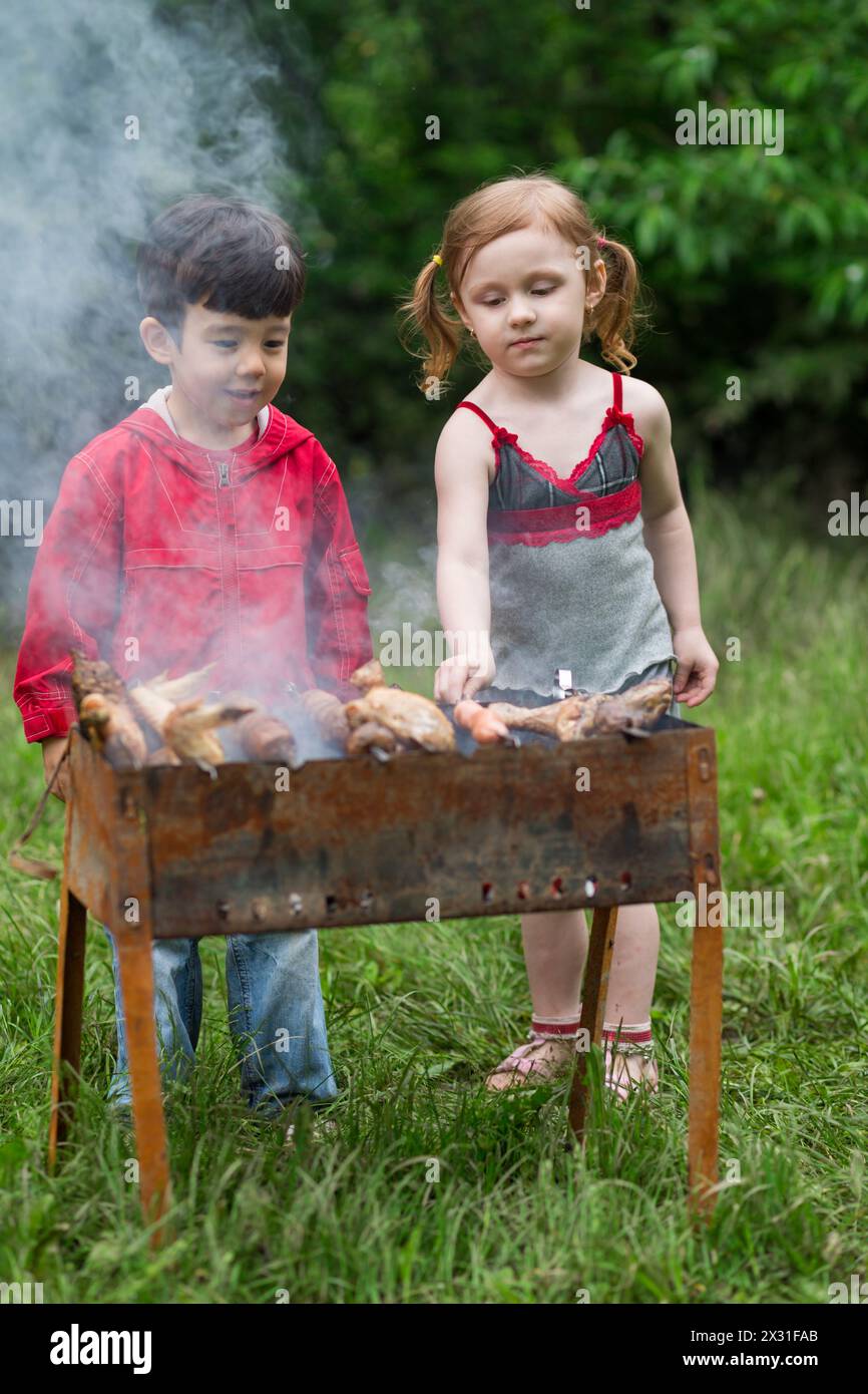 Little girl and boy making barbecue on the grill on nature Stock Photo ...