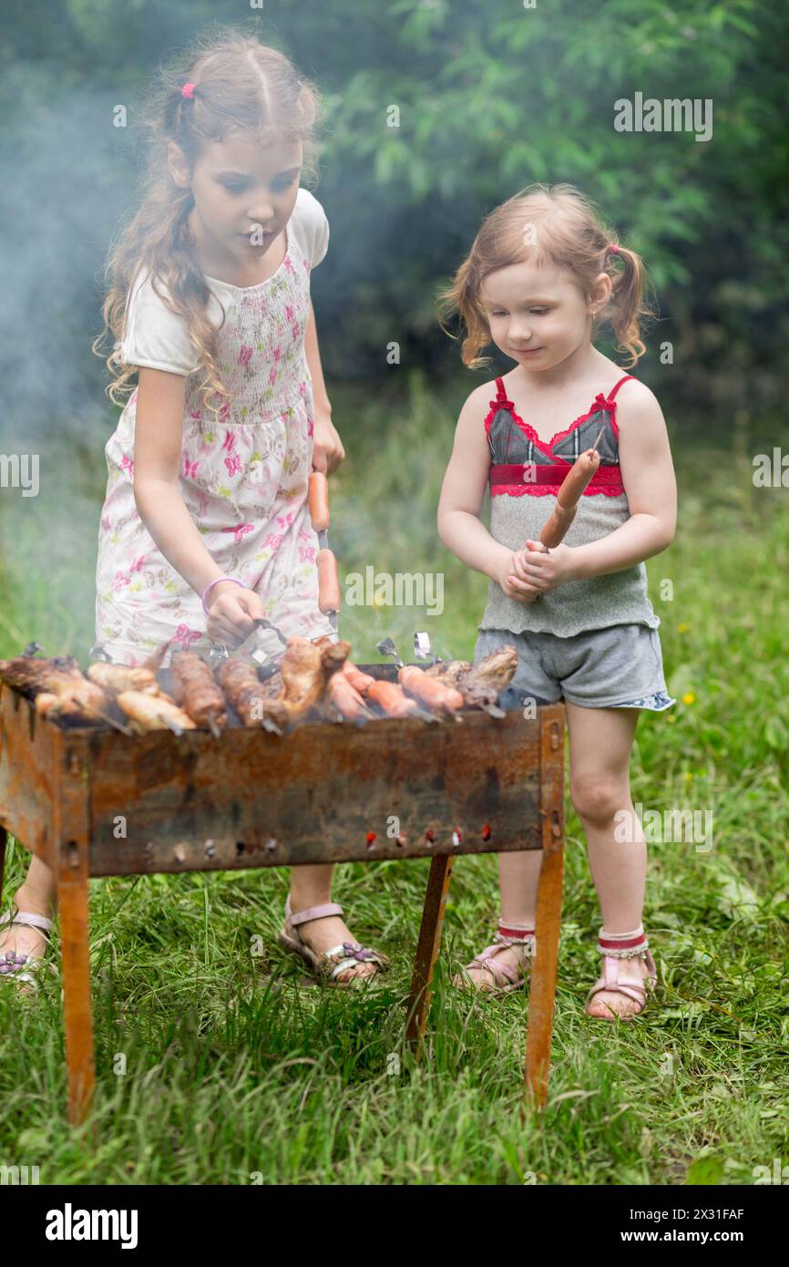 Two little girl making barbecue on the grill on nature Stock Photo - Alamy