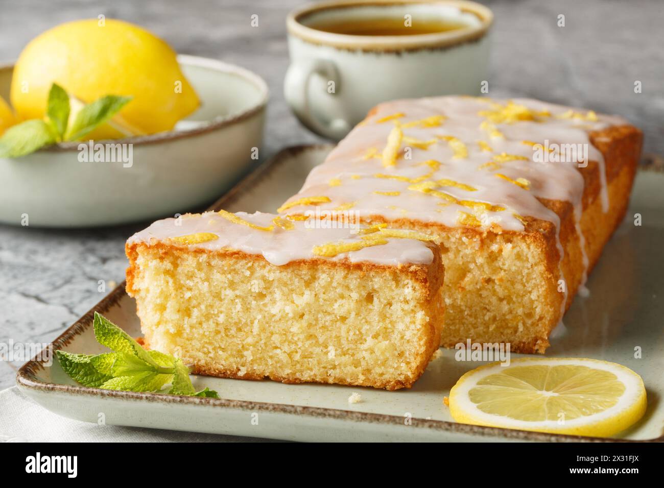 Glazed lemon pound cake loaf with lemon zest closeup on the plate on ...