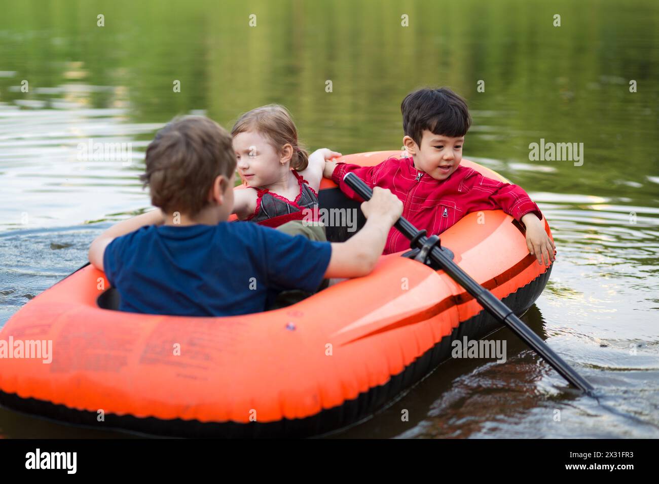 Three little friends floating in a rubber boat on the pond Stock Photo ...