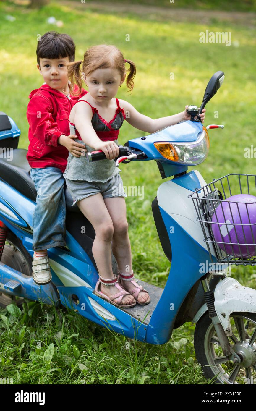 Korean boy and caucasian girl on a blue scooter on nature Stock Photo ...