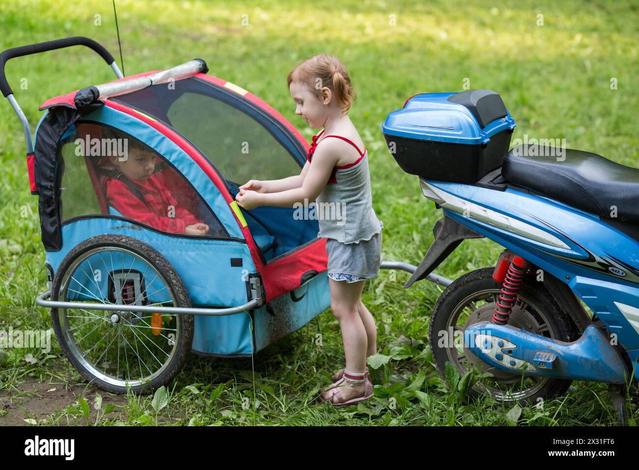 The girl closes the little boy in cart trailers to motor scooters Stock ...