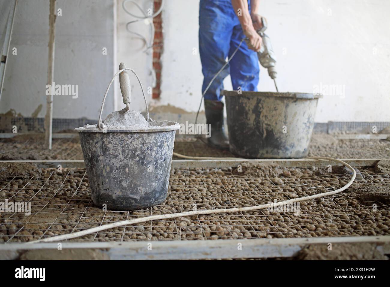 Room with expanded clay aggregate on the floor and worker with tool ...