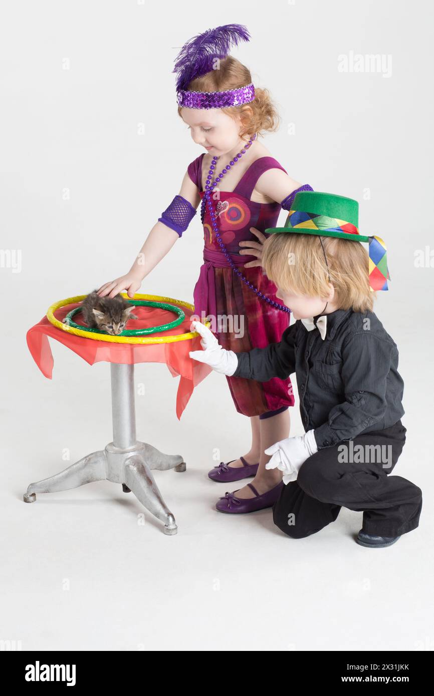 Little girl and boy in costumes of magicians next to the small round ...